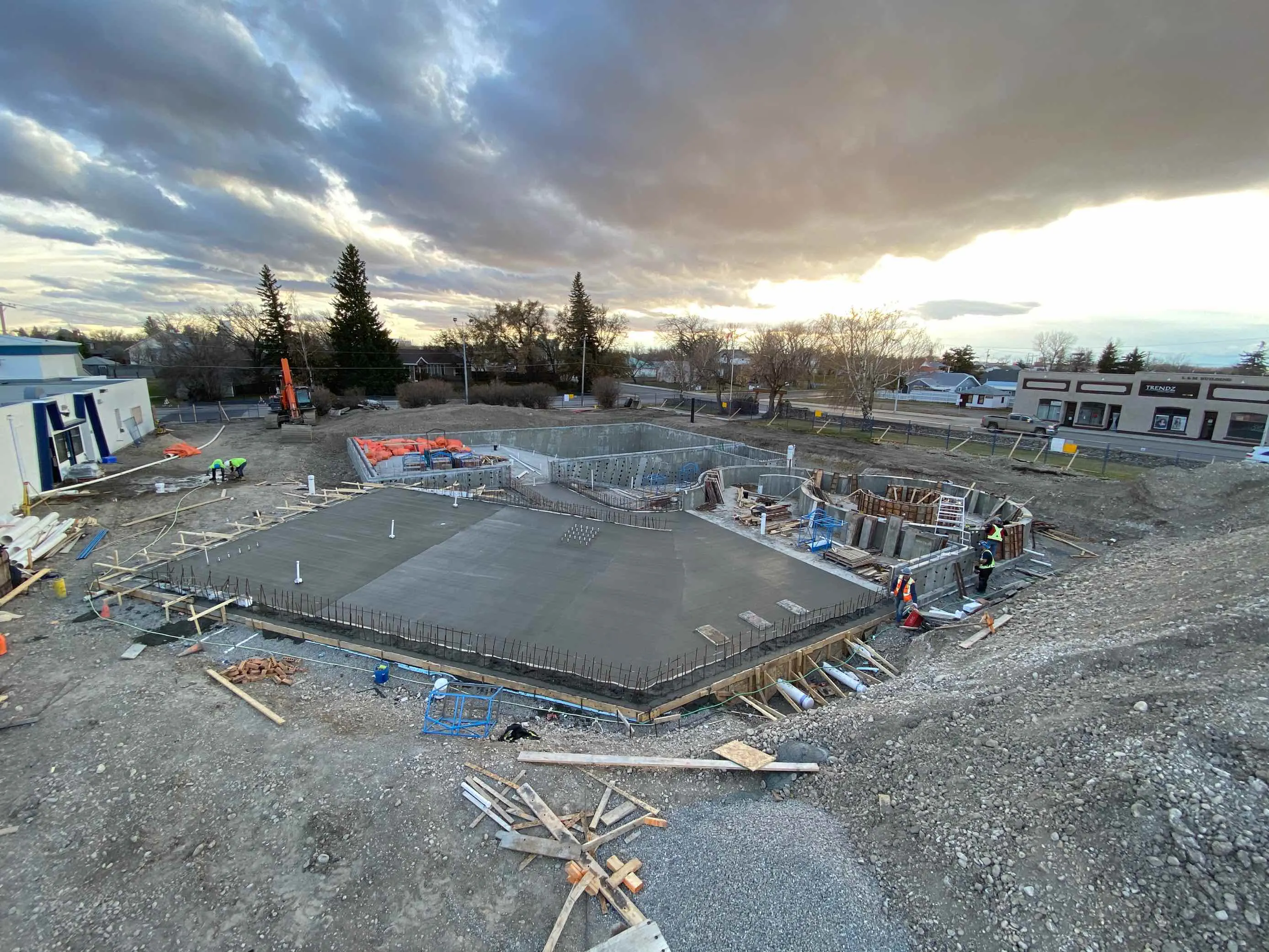 A construction site at sunset with a concrete foundation being poured ...