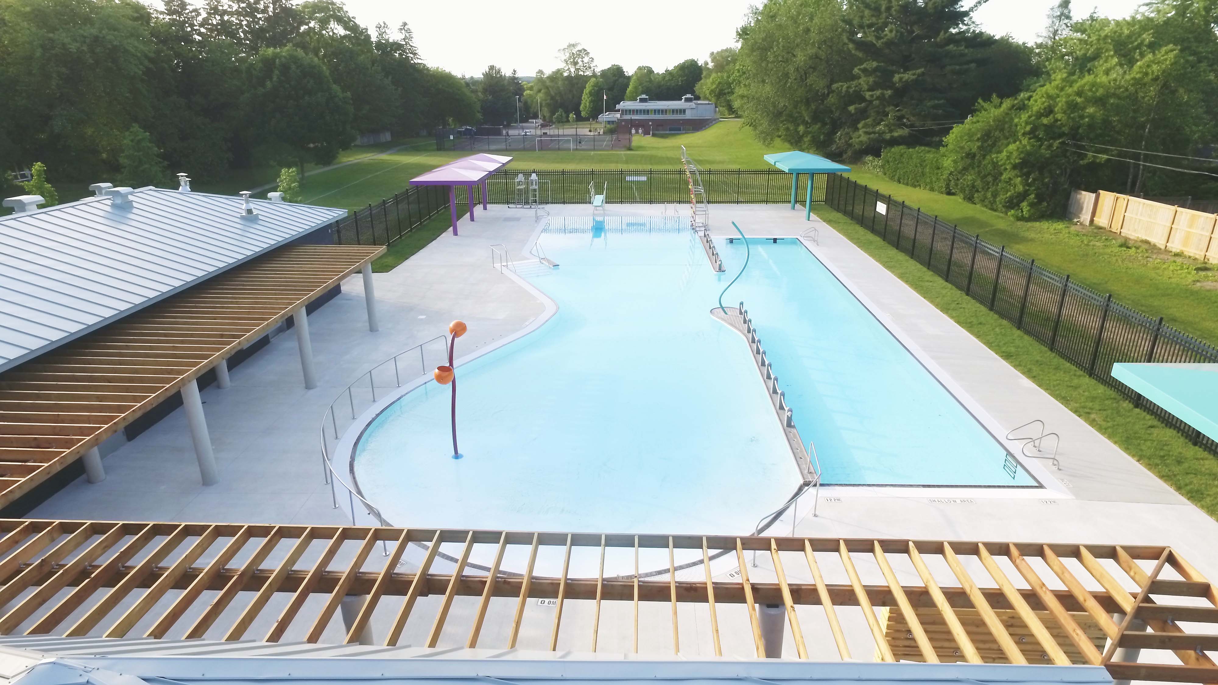 An aerial view of an outdoor pool. On one side there is a curved, zero ...