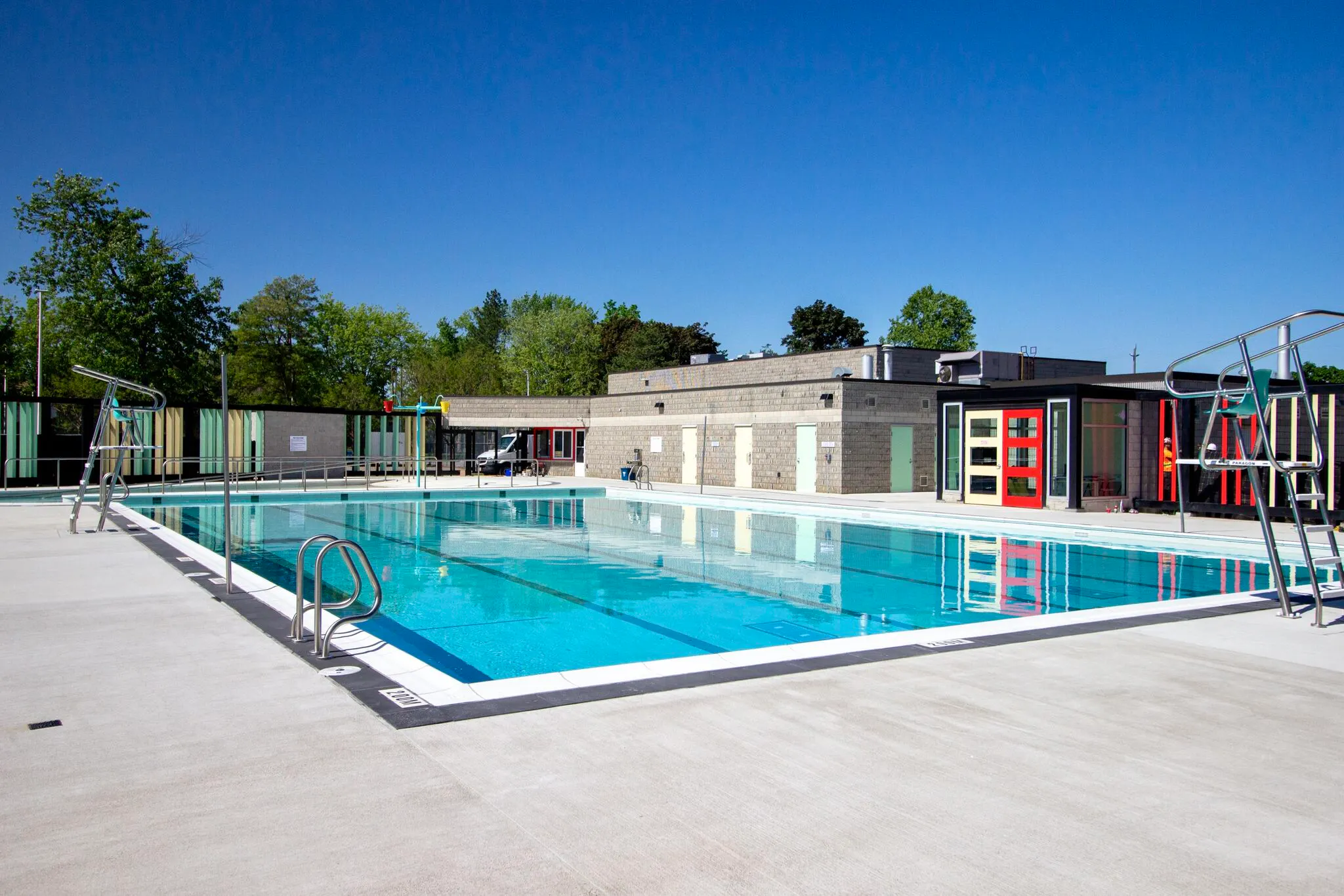 An outdoor lap pool on a sunny day with clear blue water, life guard ...