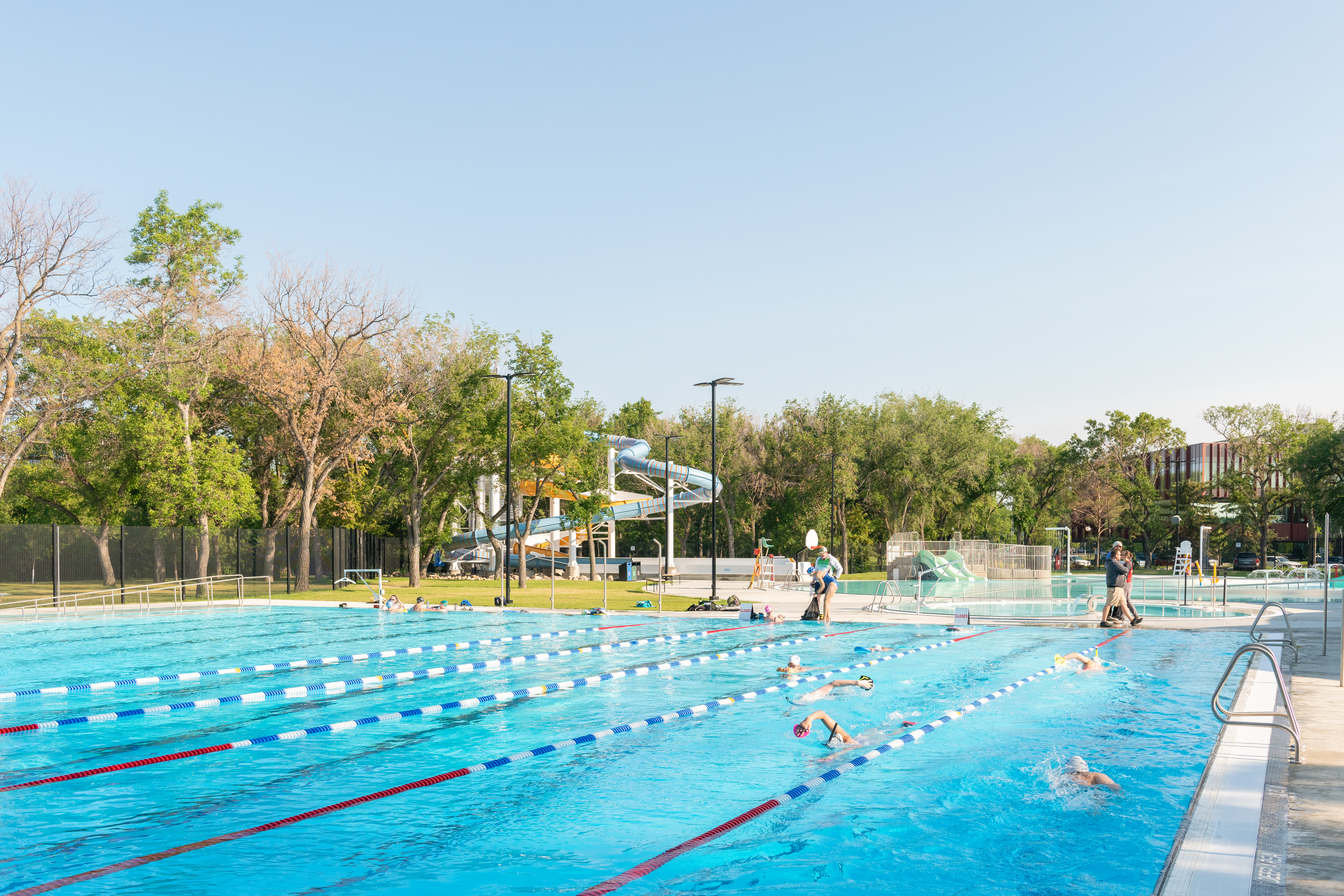 People swimming laps in an outdoor lap pool with red, blue and white ...