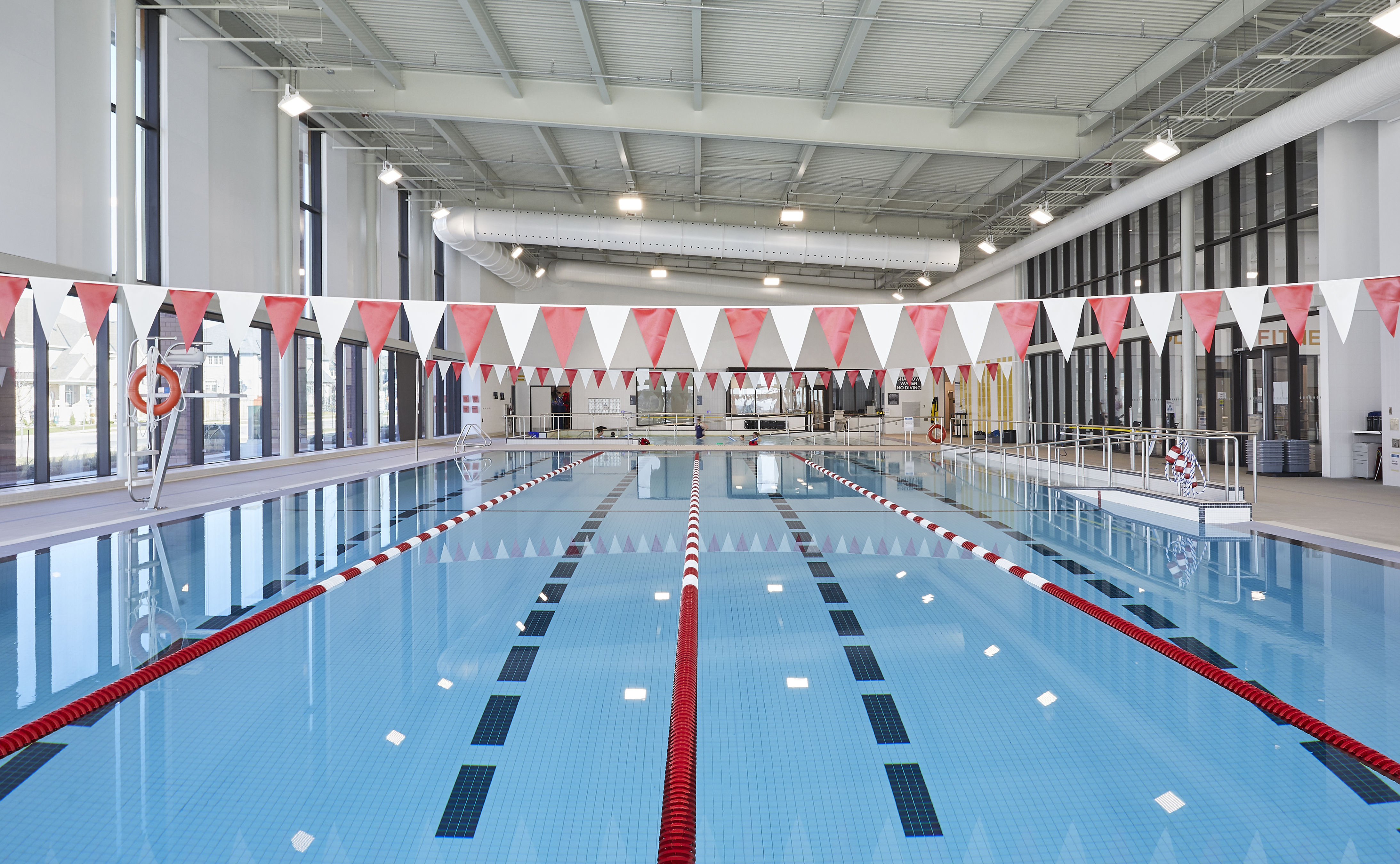 A modern indoor lap pool with red and white lane line dividers ...