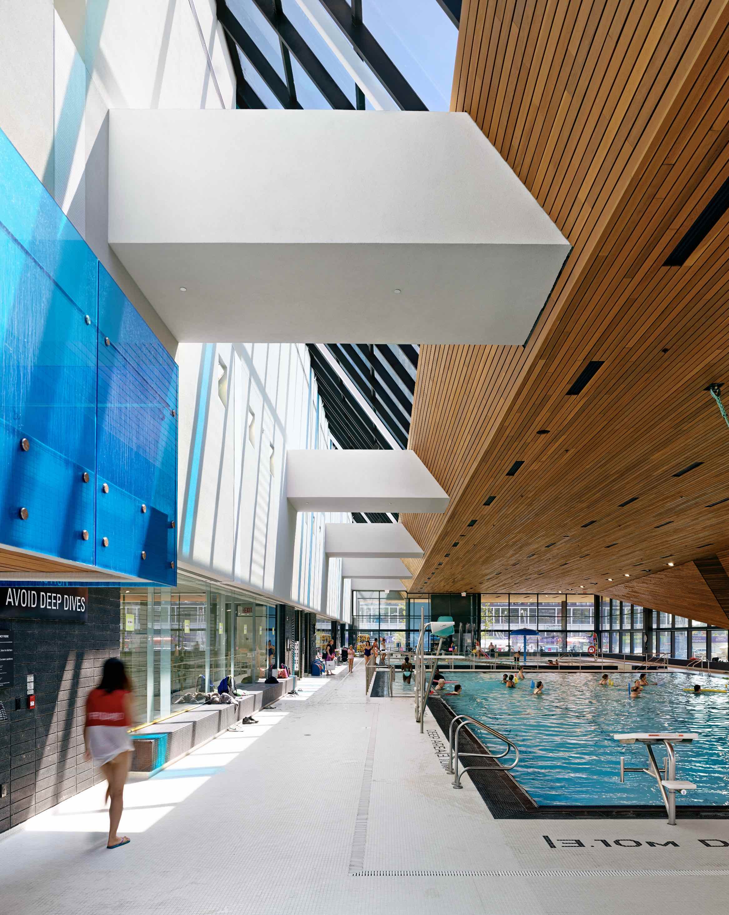 A spacious indoor pool with a modern wooden ceiling, large windows, and ...
