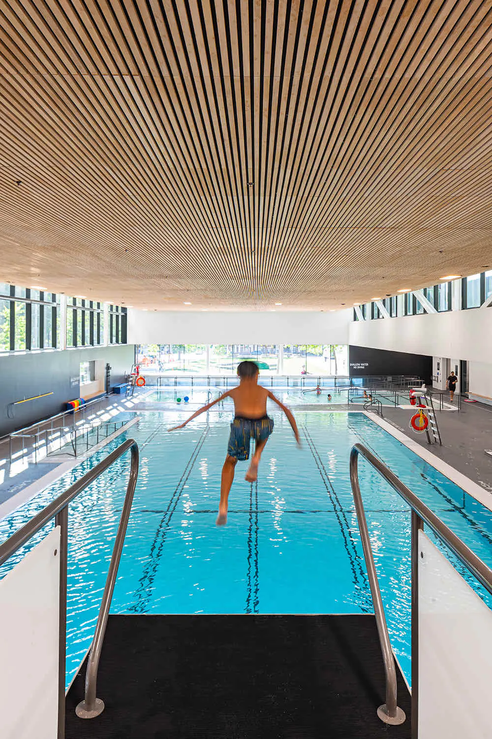 A person mid-jump into a large indoor swimming pool with a modern ...