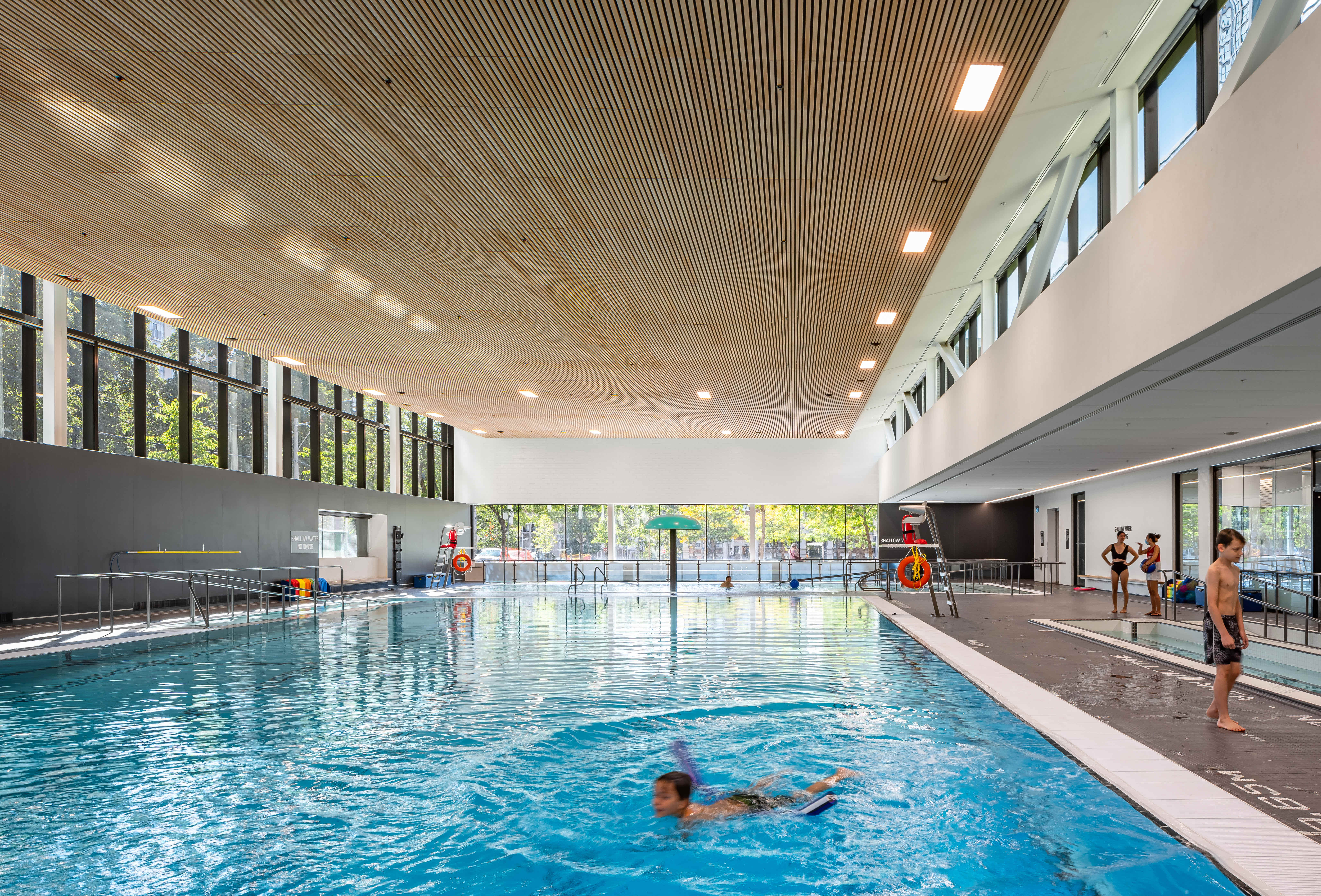 A spacious indoor pool with swimmers, a wooden ceiling, and large ...