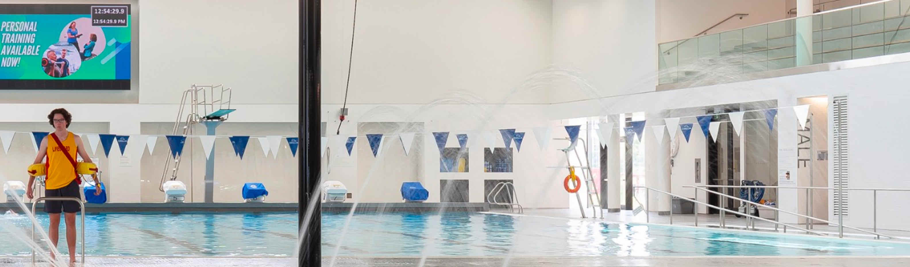 An indoor pool area with a lifeguard standing near water features and a ...