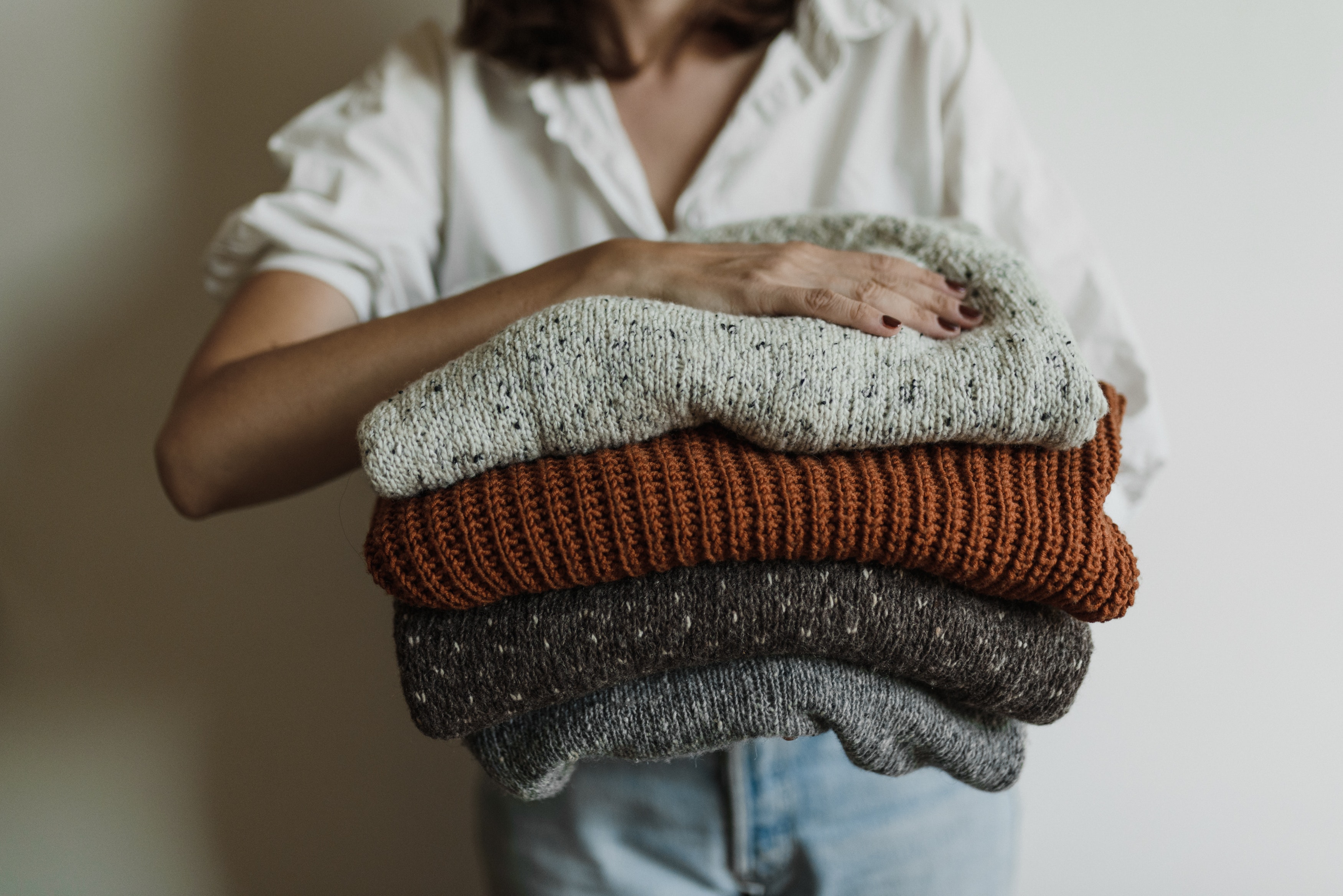 Woman holding three sweaters