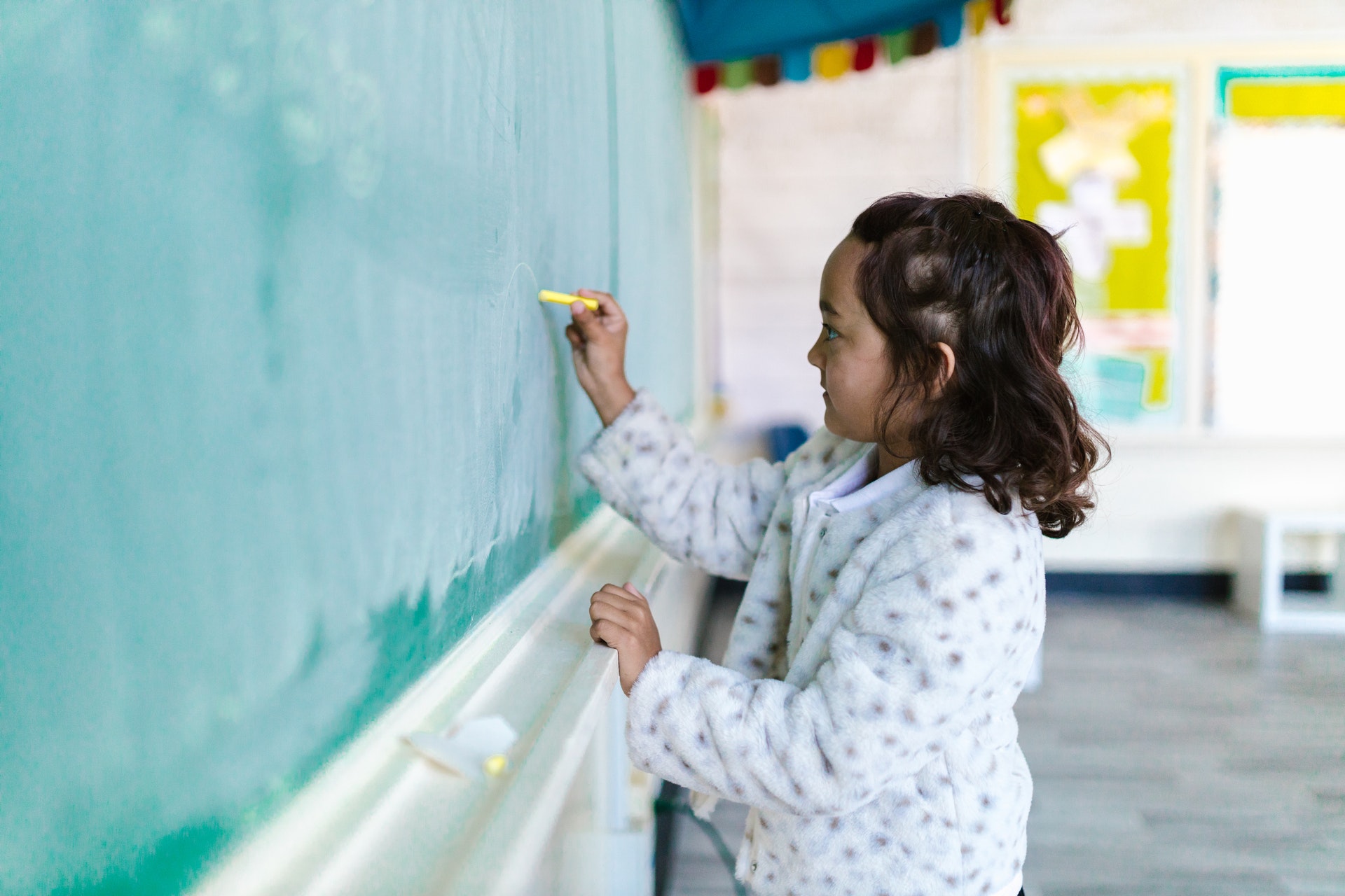 Young girl stands at a chalkboard and works on subtraction activities.